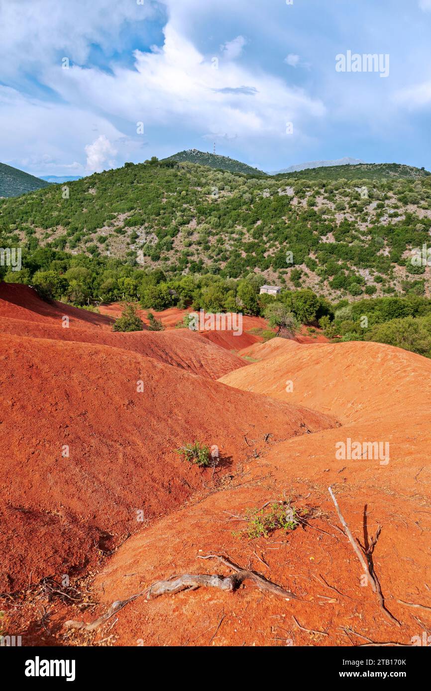 Red clay terrain with green mountainside at the back, a rare geological ...