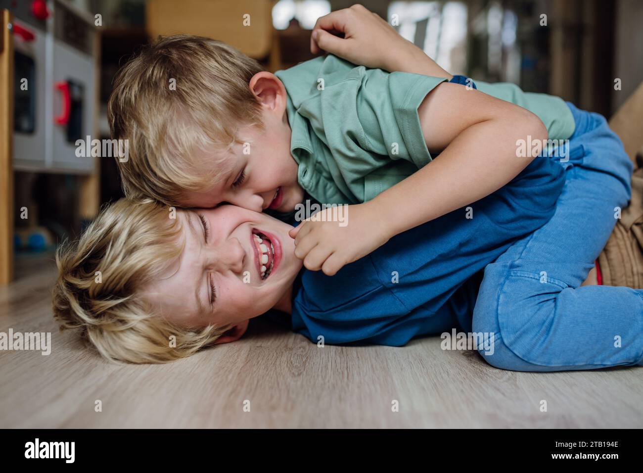 Two little boys fighting on the floor, brothers having fun at home ...