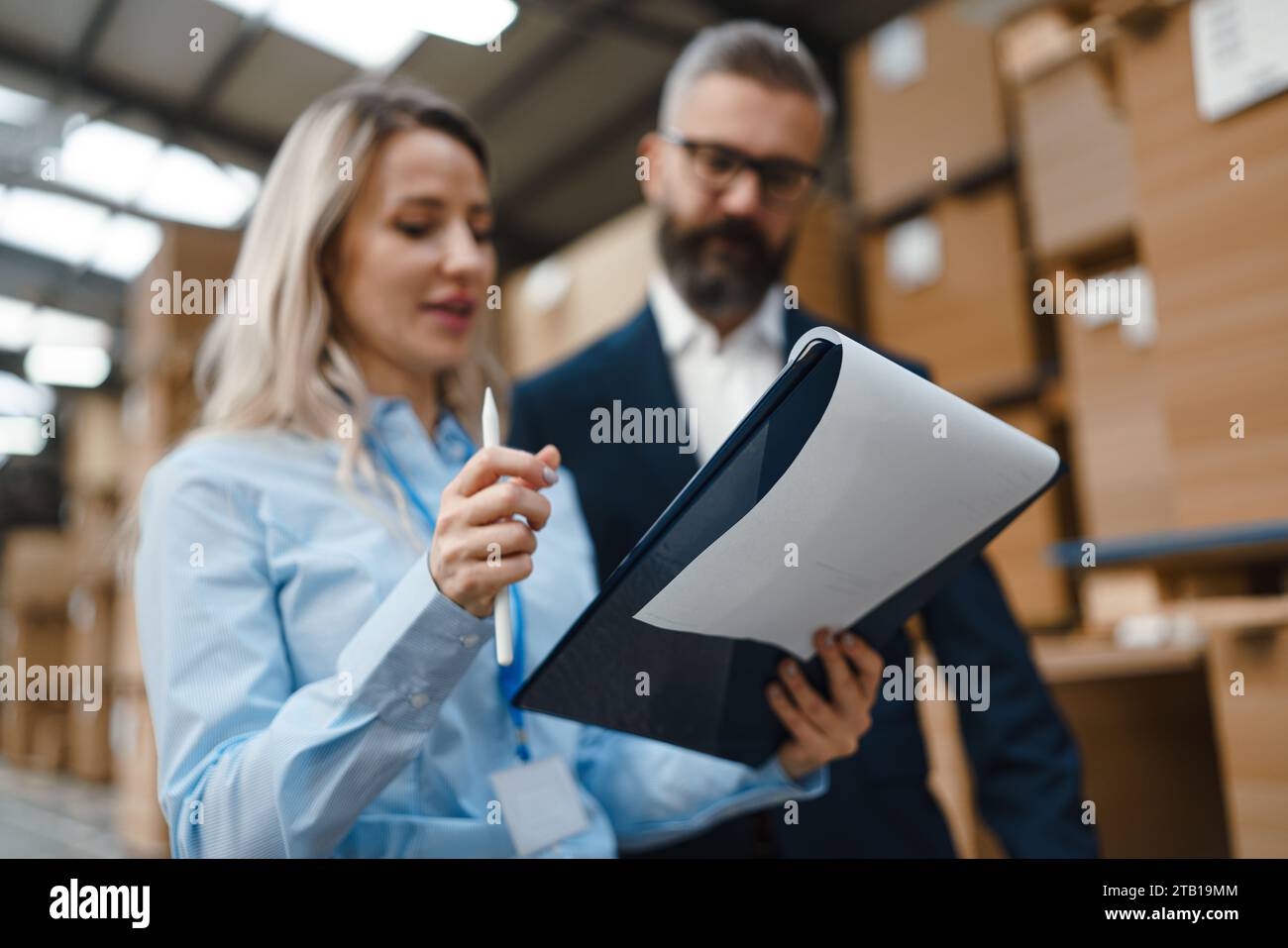 Female warehouse manager talking with logistics employee in warehouse ...