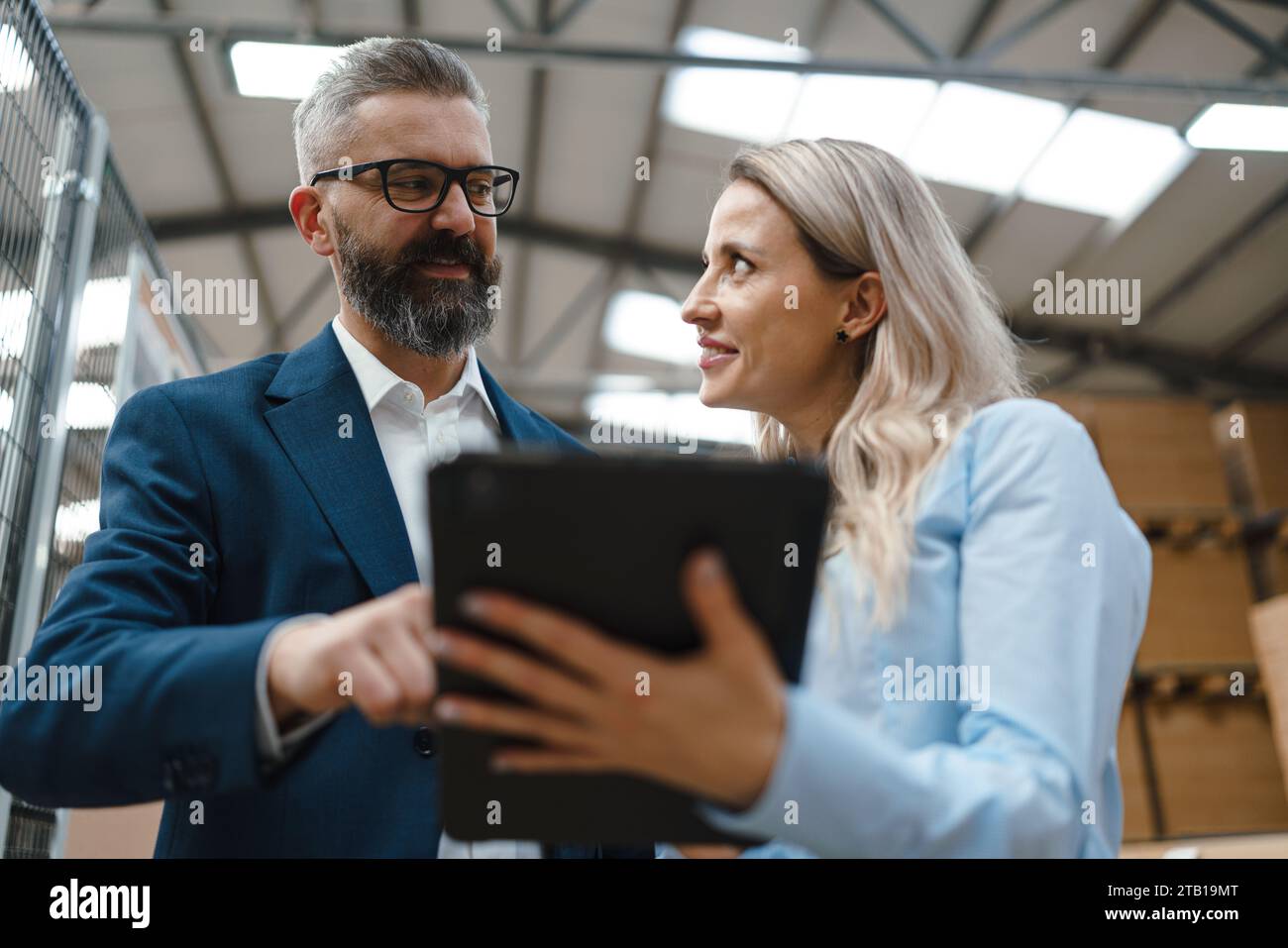 Female warehouse manager talking with logistics employee in warehouse ...