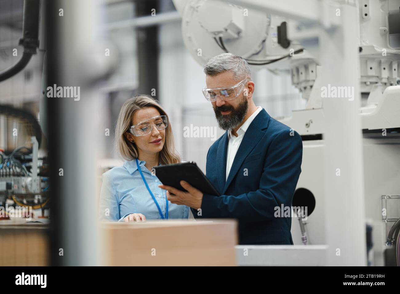 Female engineer and male supervisor standing in modern industrial ...