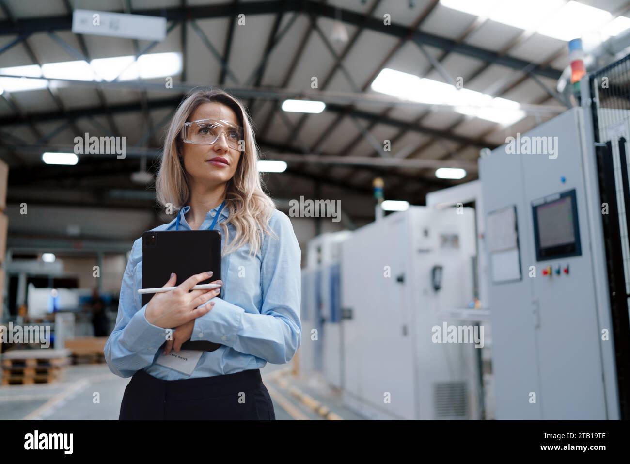Female manager standing in modern industrial factory. Manufacturing ...