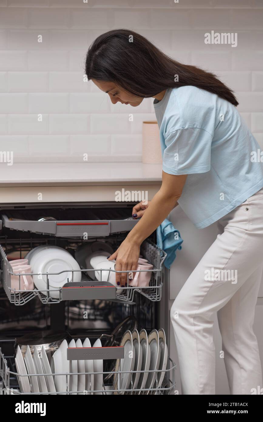 pretty woman loading dishes to open automatic built-in dishwasher ...