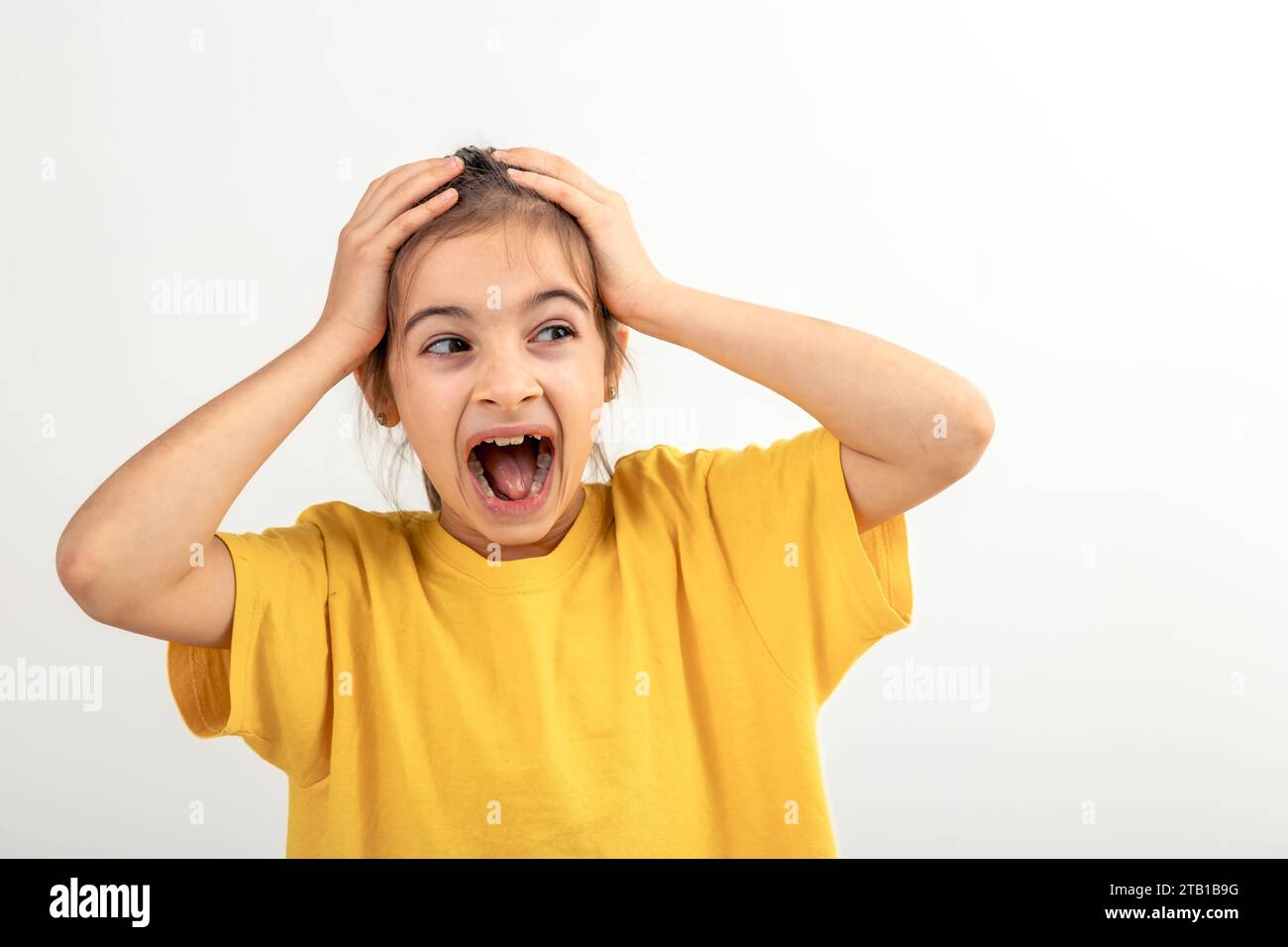 Little desperate girl looking panic, holding her head with both hands ...