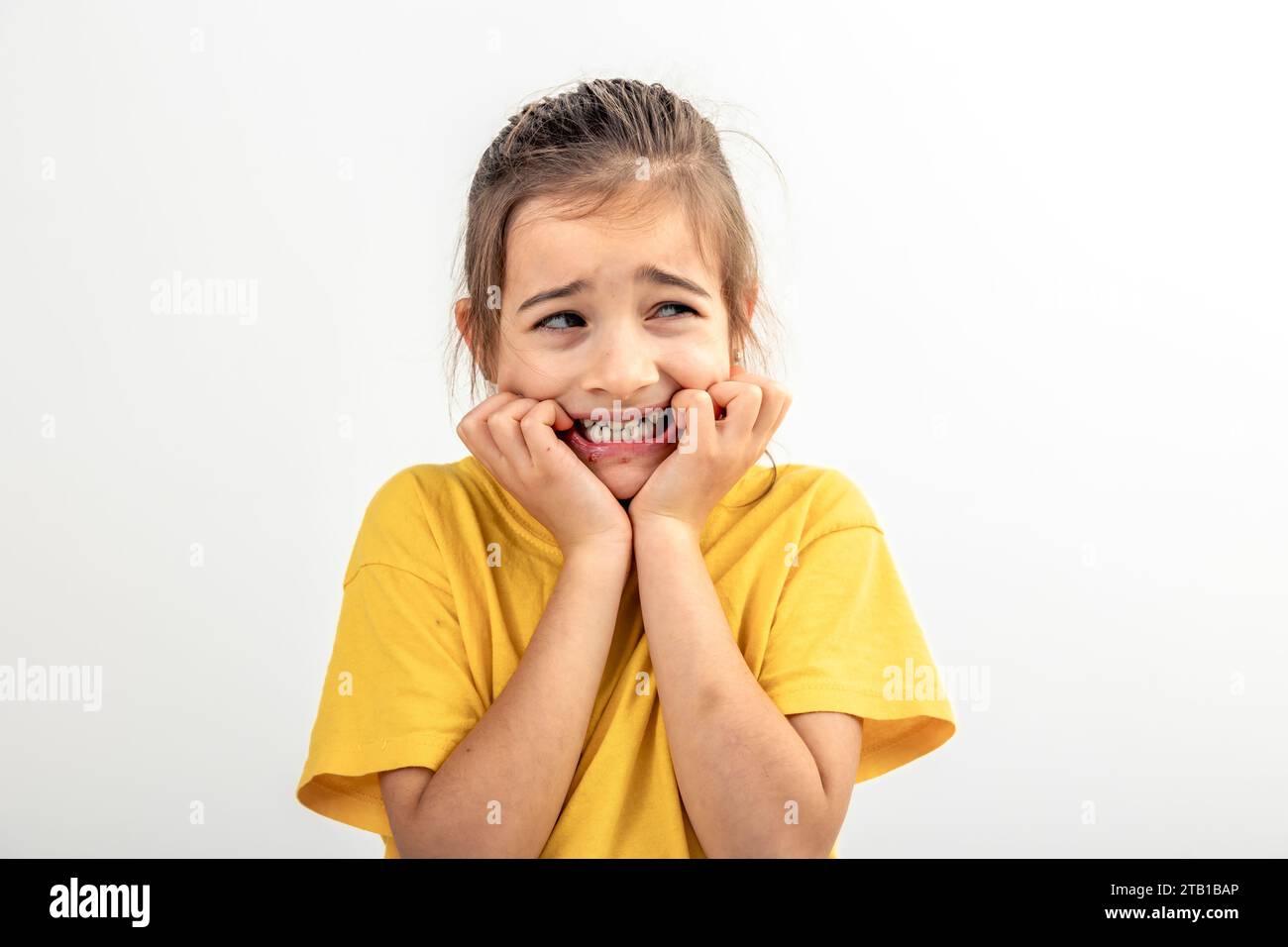 Scared and anxious girl, biting her fingernails on a white background ...