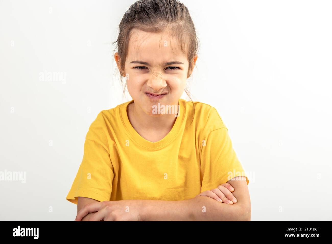 Angry little girl with folded hands on a white background isolated ...