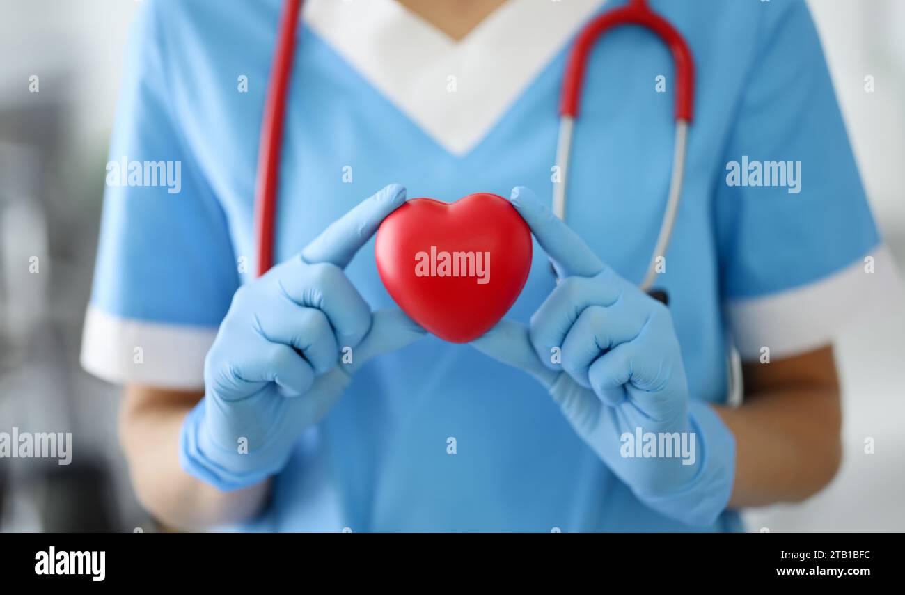 Doctor in blue suit, gloves and with red stethoscope hold symbol Stock ...