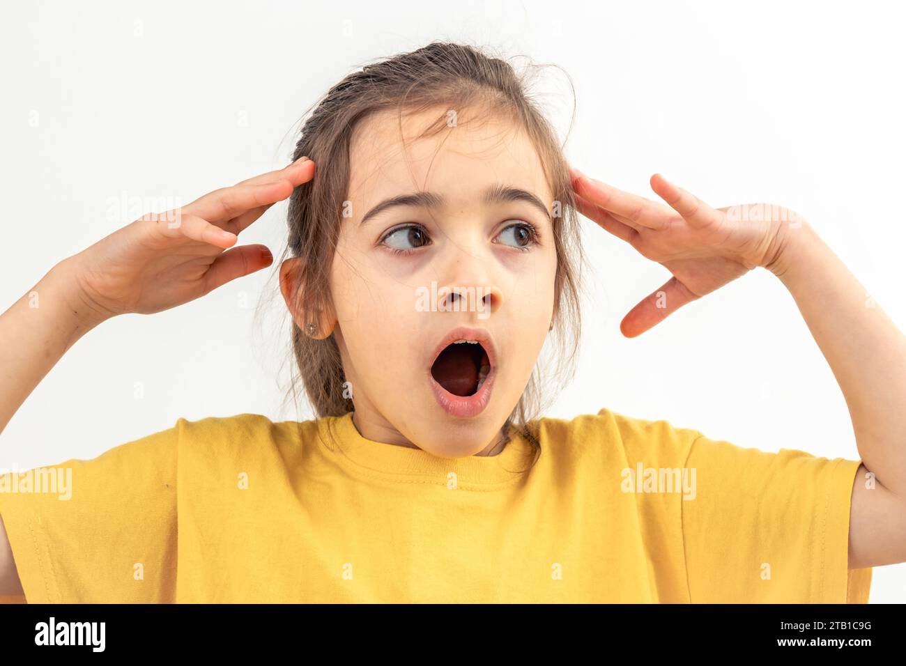 Little desperate girl looking panic, holding her head with both hands ...