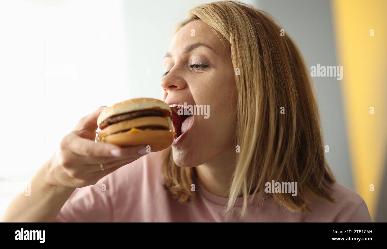 Young woman bites her mouth wide open hamburger Stock Photo - Alamy