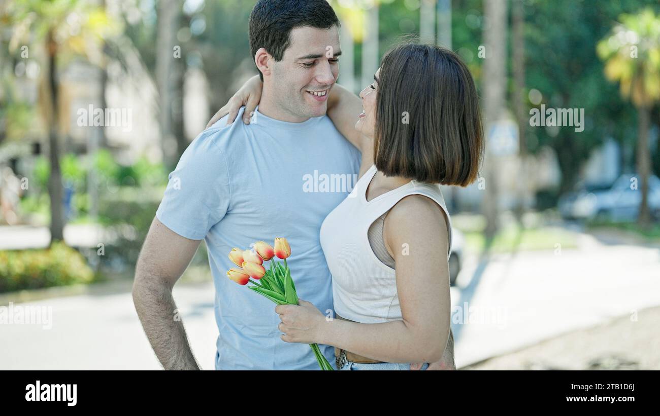Beautiful couple surprise with bouquet of flowers hugging each other at ...