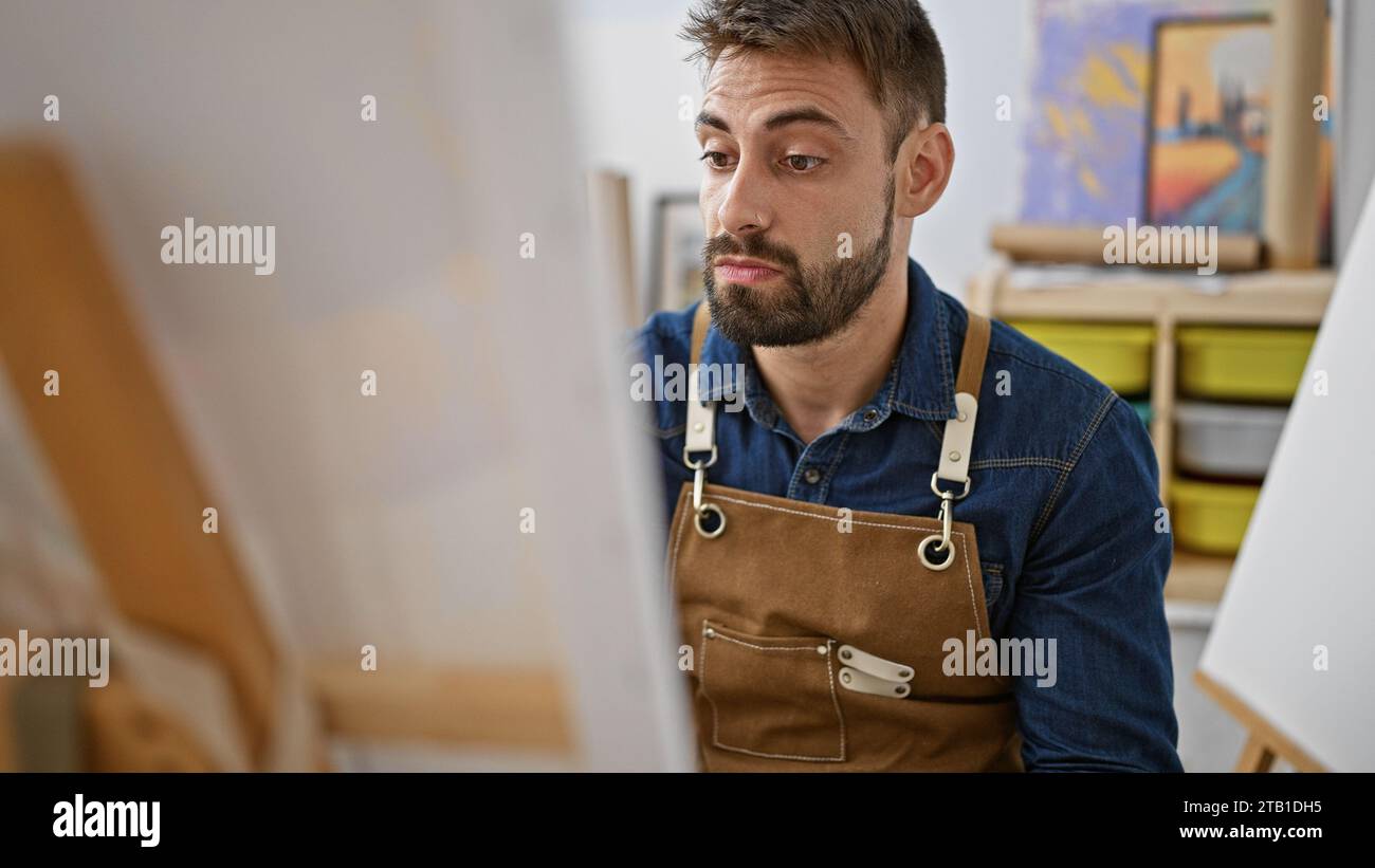Happy young hispanic man drawing with confidence, art studio’s resident ...