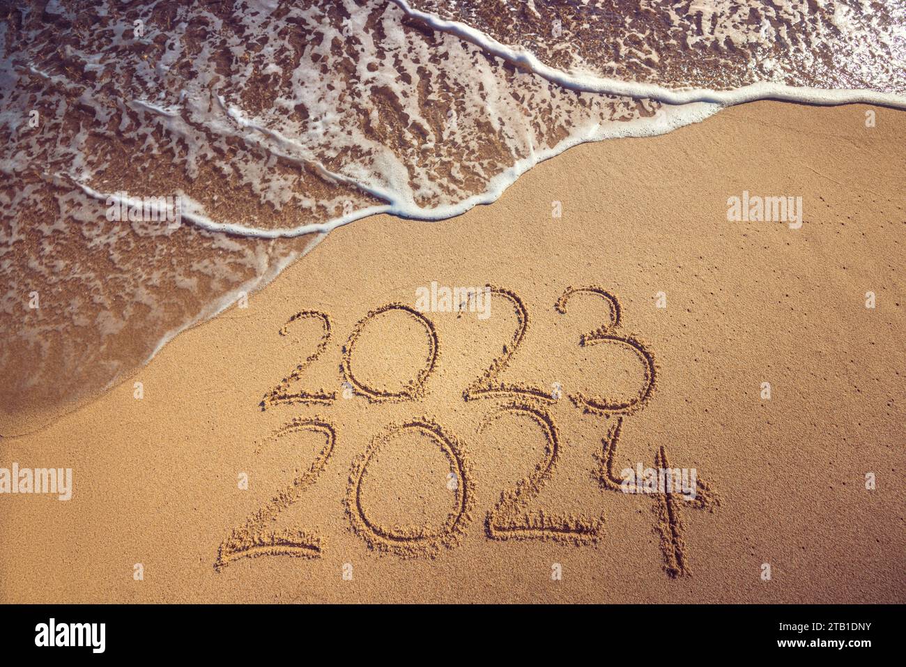 Starting new year 2024 ending 2023 text on the beach sand and splashing ...