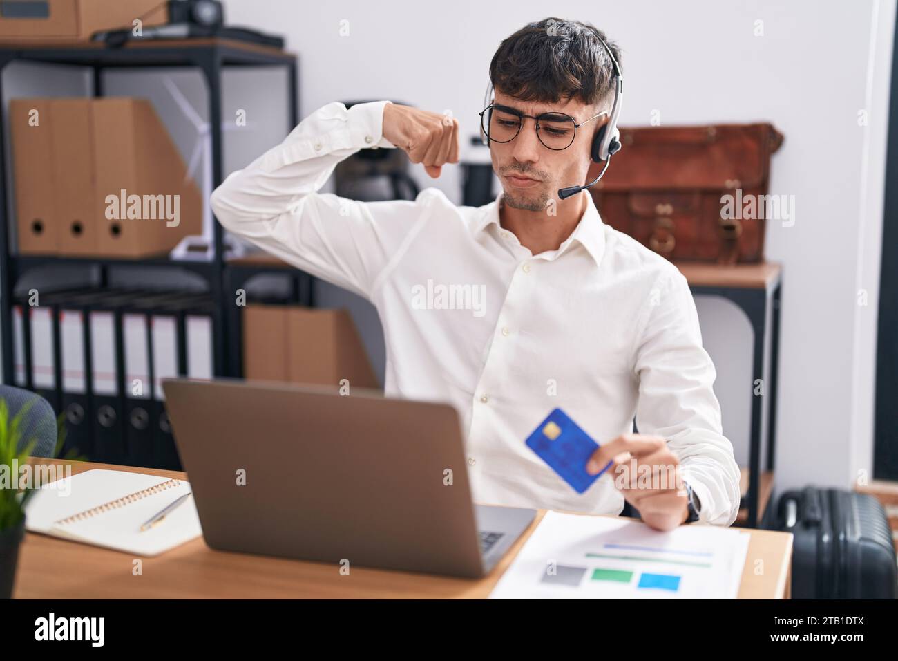 Young hispanic man working using computer laptop holding credit card ...