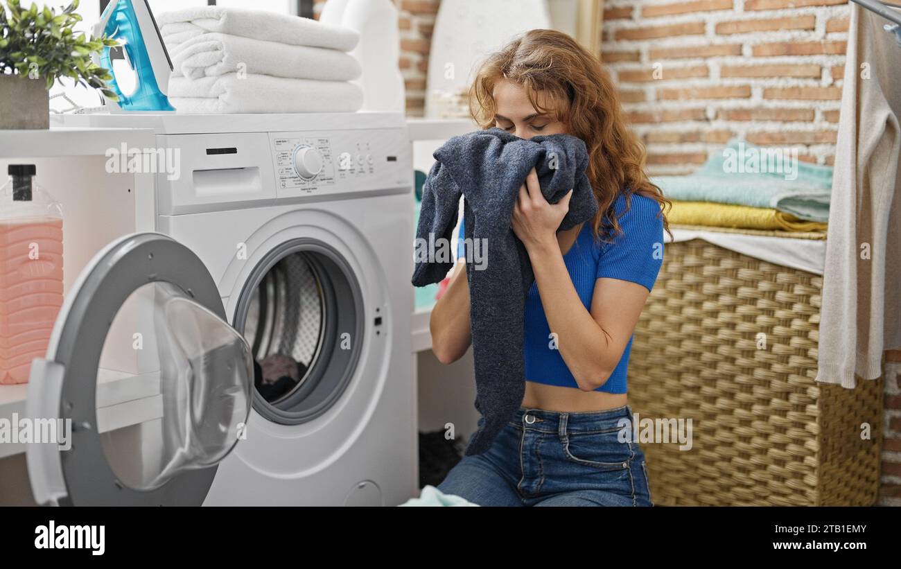 Young woman smelling clothes at laundry room Stock Photo - Alamy
