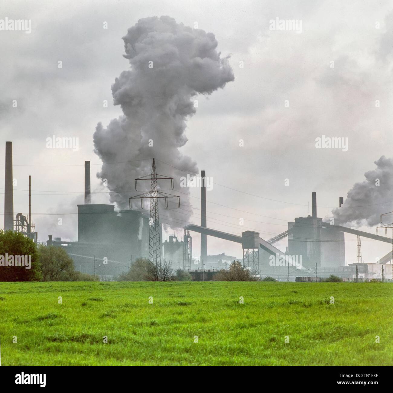 Industrial plant with lots of smoke and fume in front of clouded sky ...
