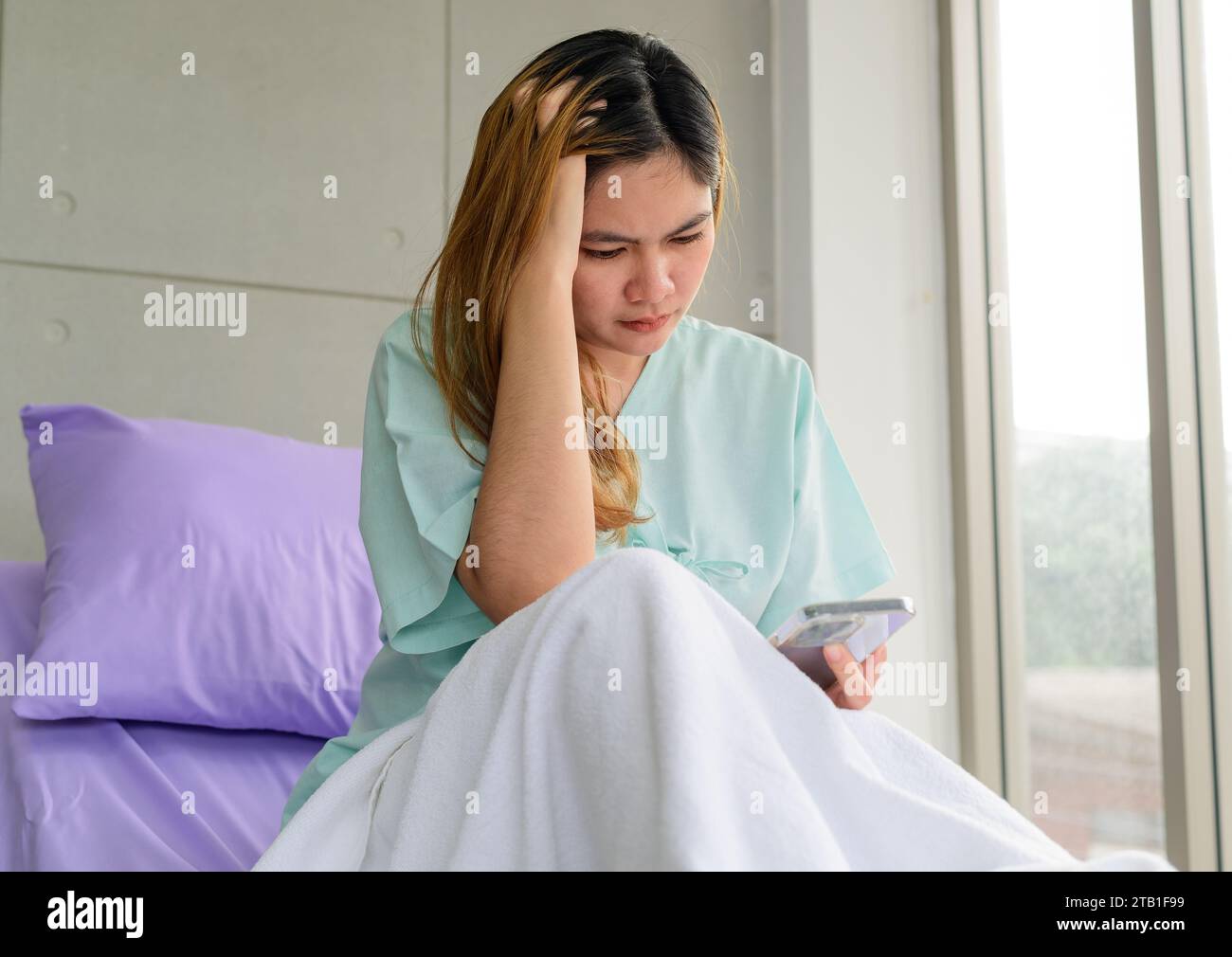 Stressed woman patient looking smartphone on hospital bed Stock Photo ...