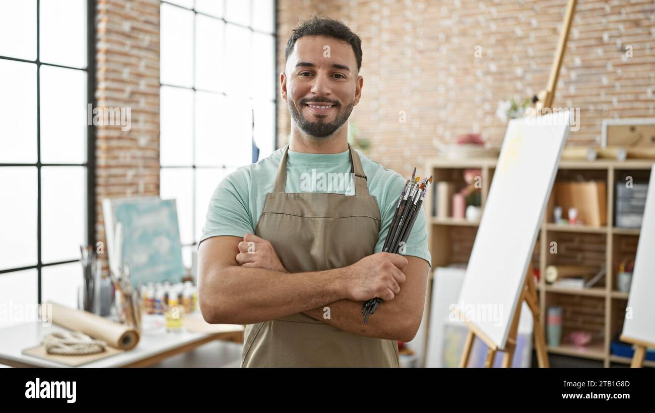 Young arab man artist standing with arms crossed gesture holding ...