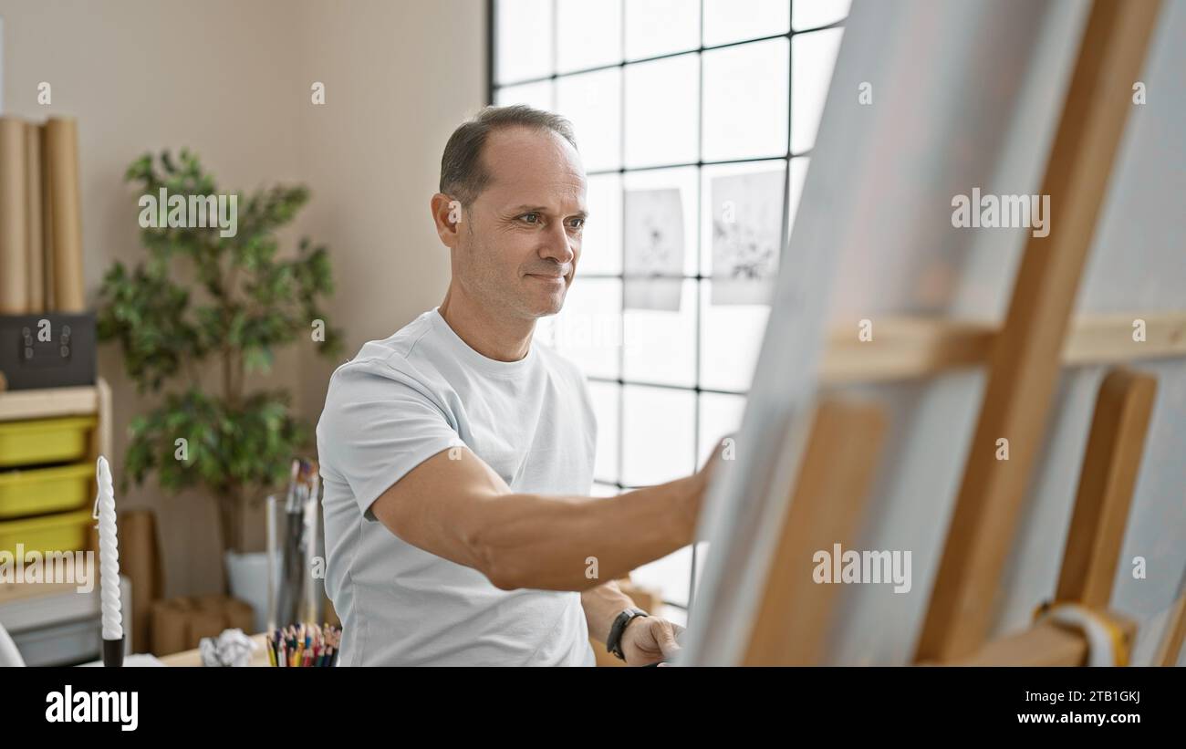 Confident middle age man, a smiling artist, thoroughly enjoys drawing ...