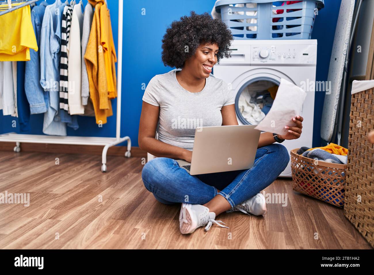 African american woman using laptop reading paperwork waiting for ...