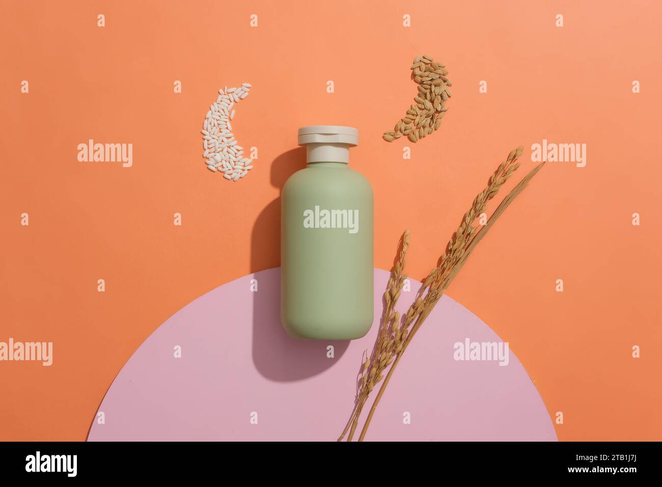 Empty label bottle in pastel green color displayed with handful of rice ...