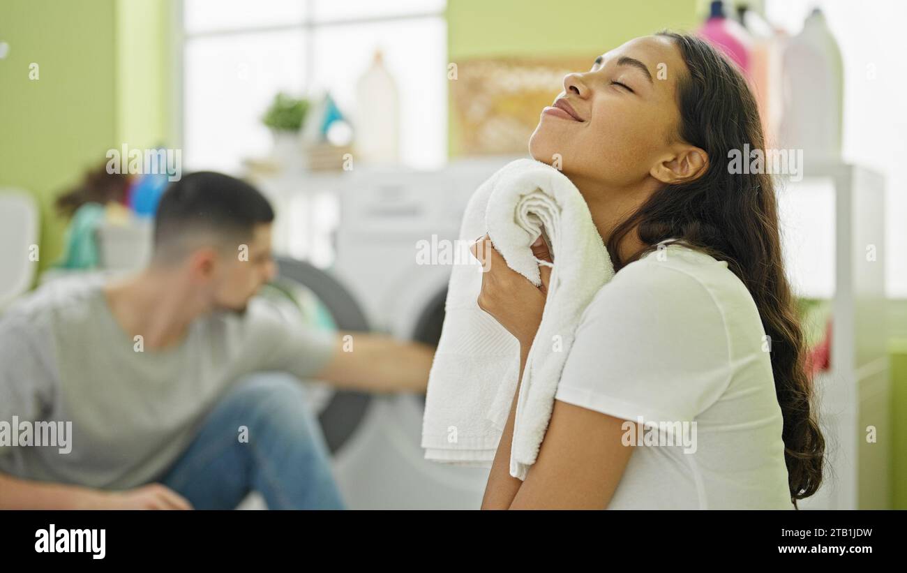 Smiling beautiful couple sitting on the floor of their laundry room, enjoying the smell of fresh ...