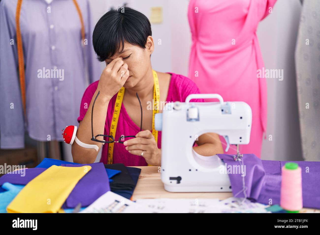 Middle age chinese woman tailor stressed using sewing machine at ...