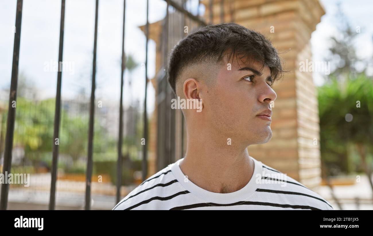 Cool, relaxed young hispanic man looking serious, standing outside on a ...