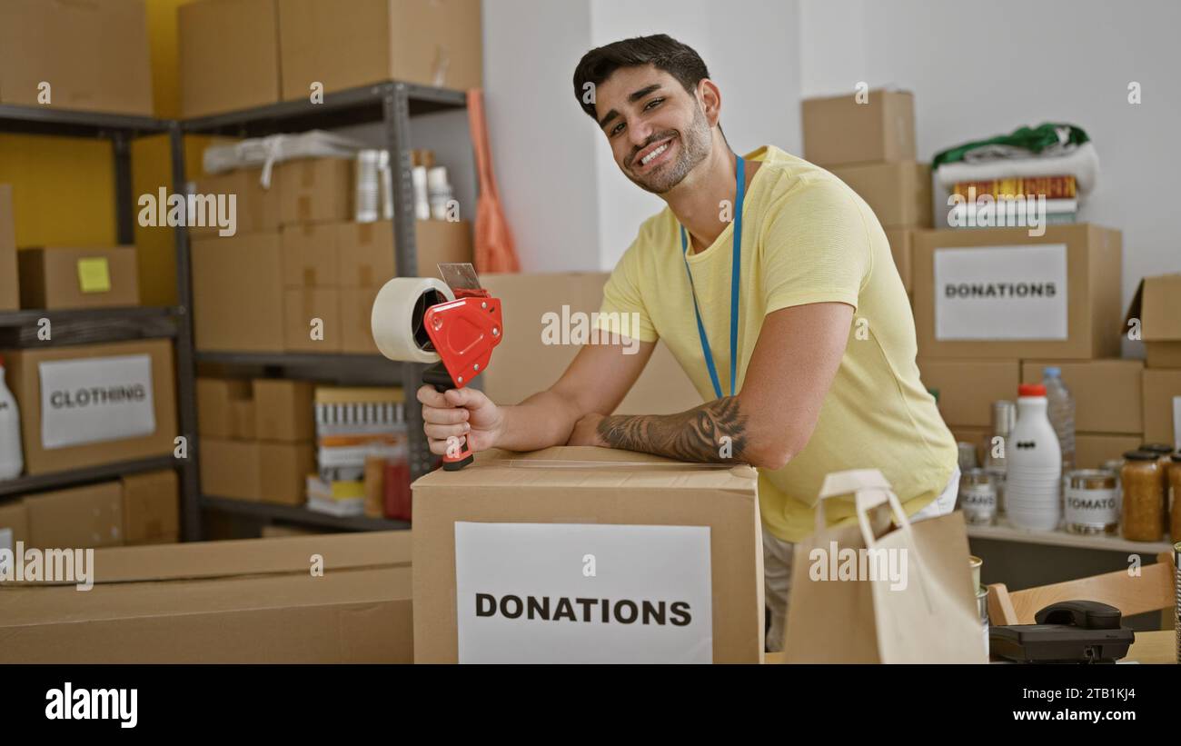 Young hispanic man volunteer smiling confident leaning on donations ...