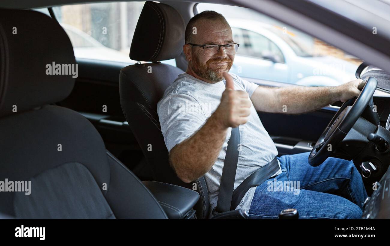 Cheery middle-aged caucasian man driving car down urban street, giving ...