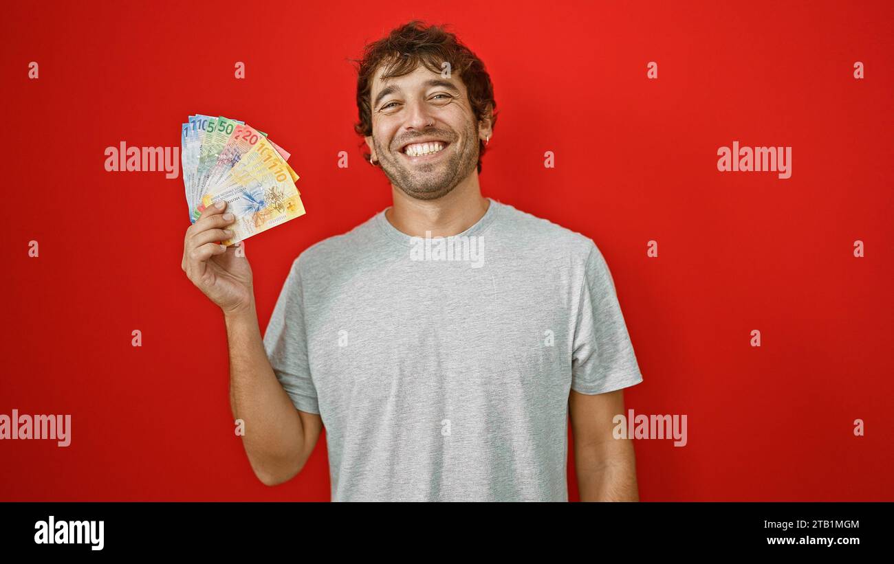 Happy young man with blond beard proudly holding up swiss franc ...
