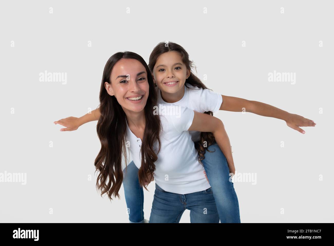 Cute smiling young brunette mother holds on back her cute little ...