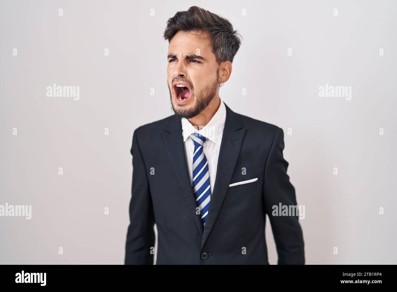 Young hispanic man with tattoos wearing business suit and tie angry and ...