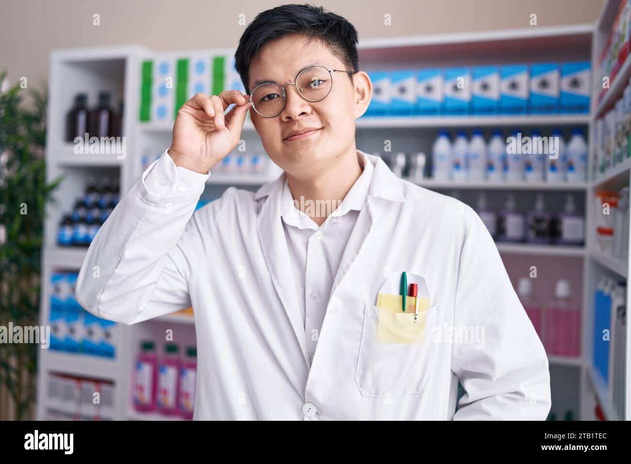 Young chinese man pharmacist smiling confident standing at pharmacy ...