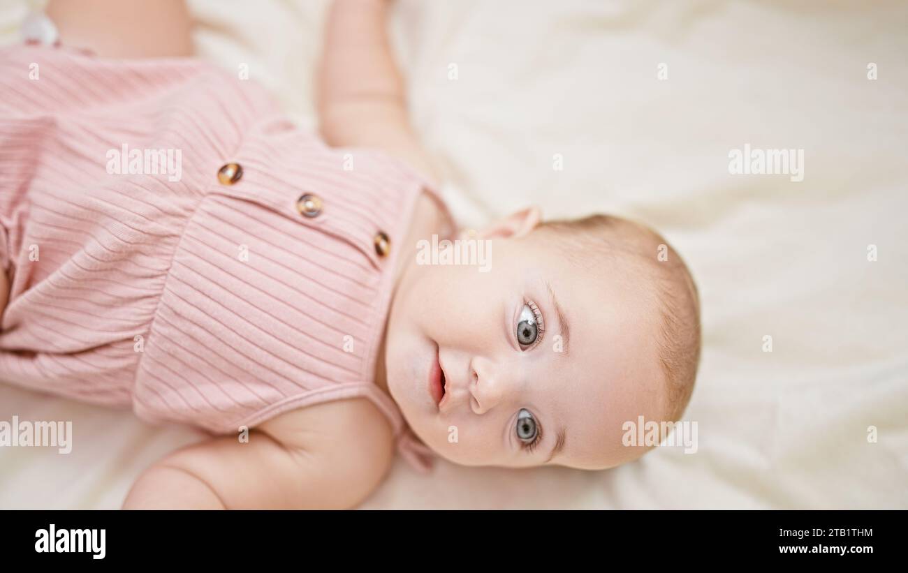 Adorable baby lies comfortably relaxed on white blanket, living the ...