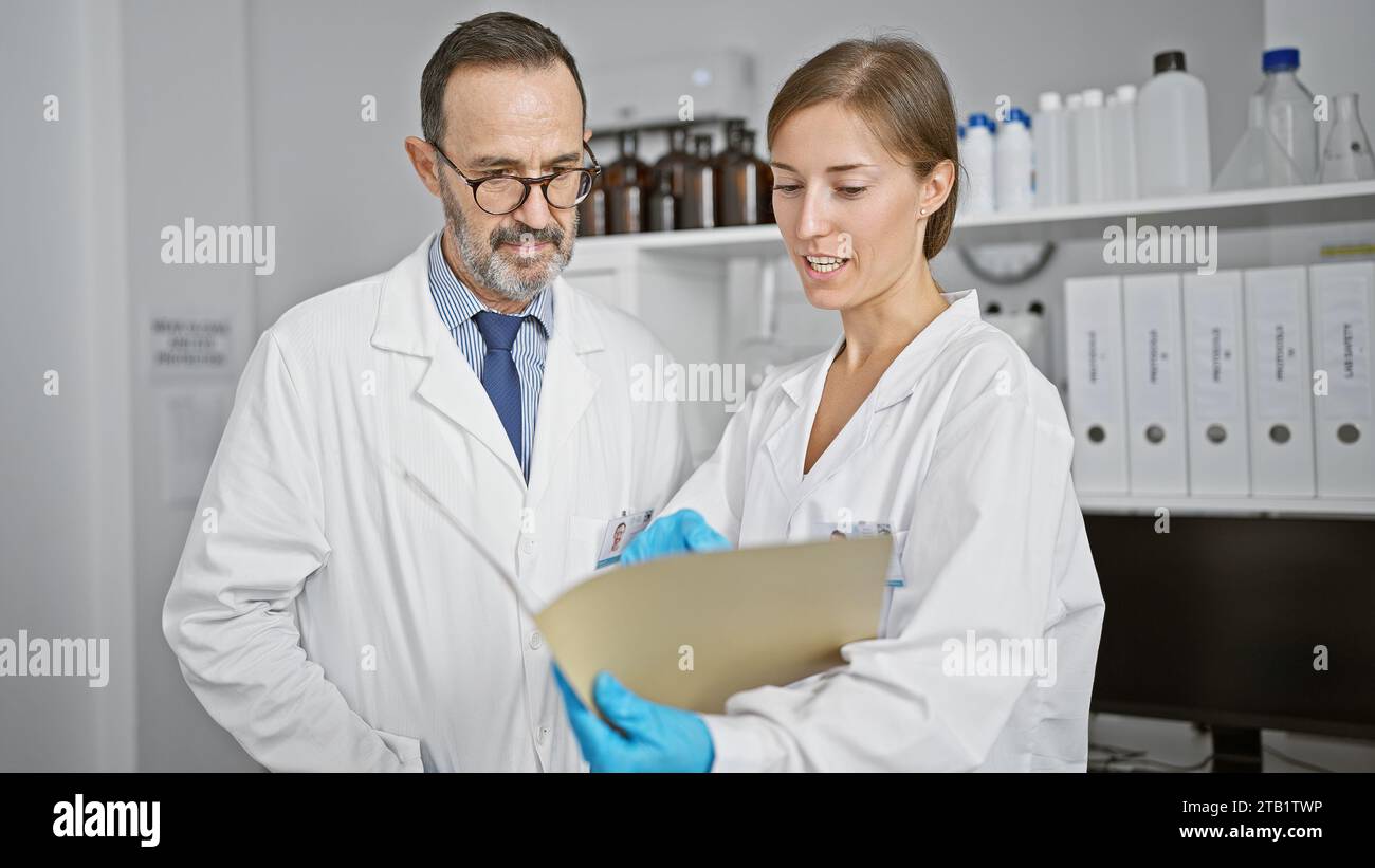 Two scientists reading document together speaking at laboratory Stock ...
