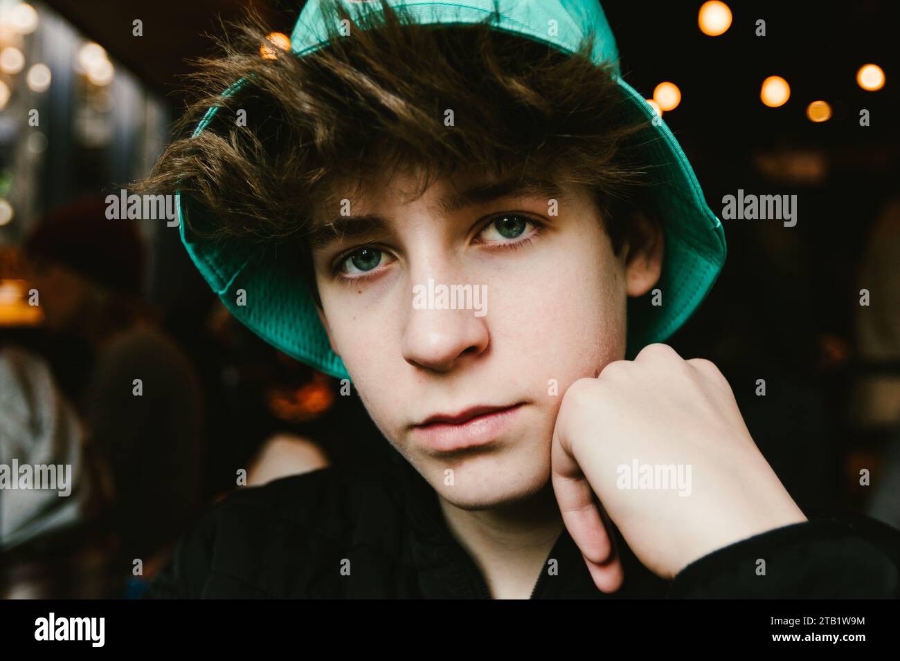 Teenage boy in green bucket hat face with bokeh light behind Stock ...