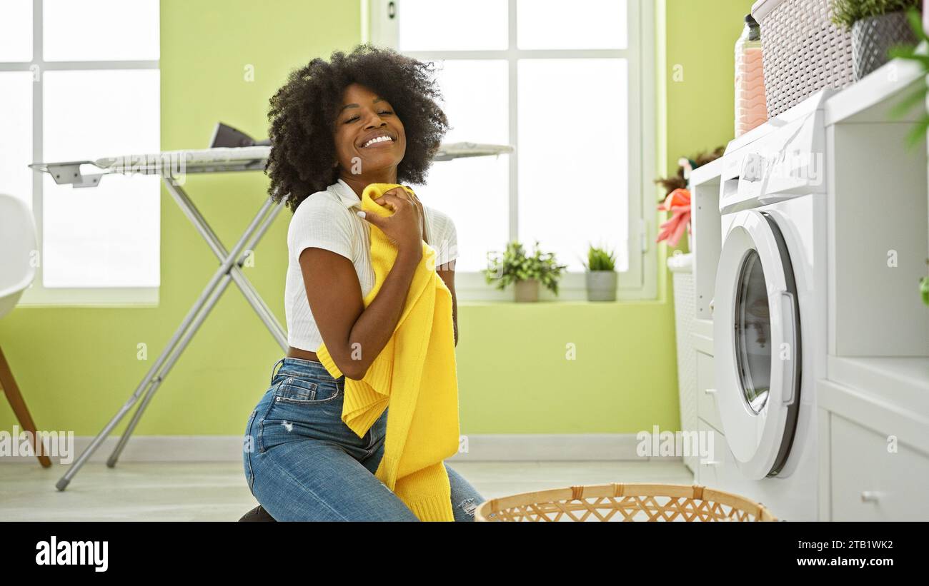 African american woman washing clothes holding clean sweater smiling at ...