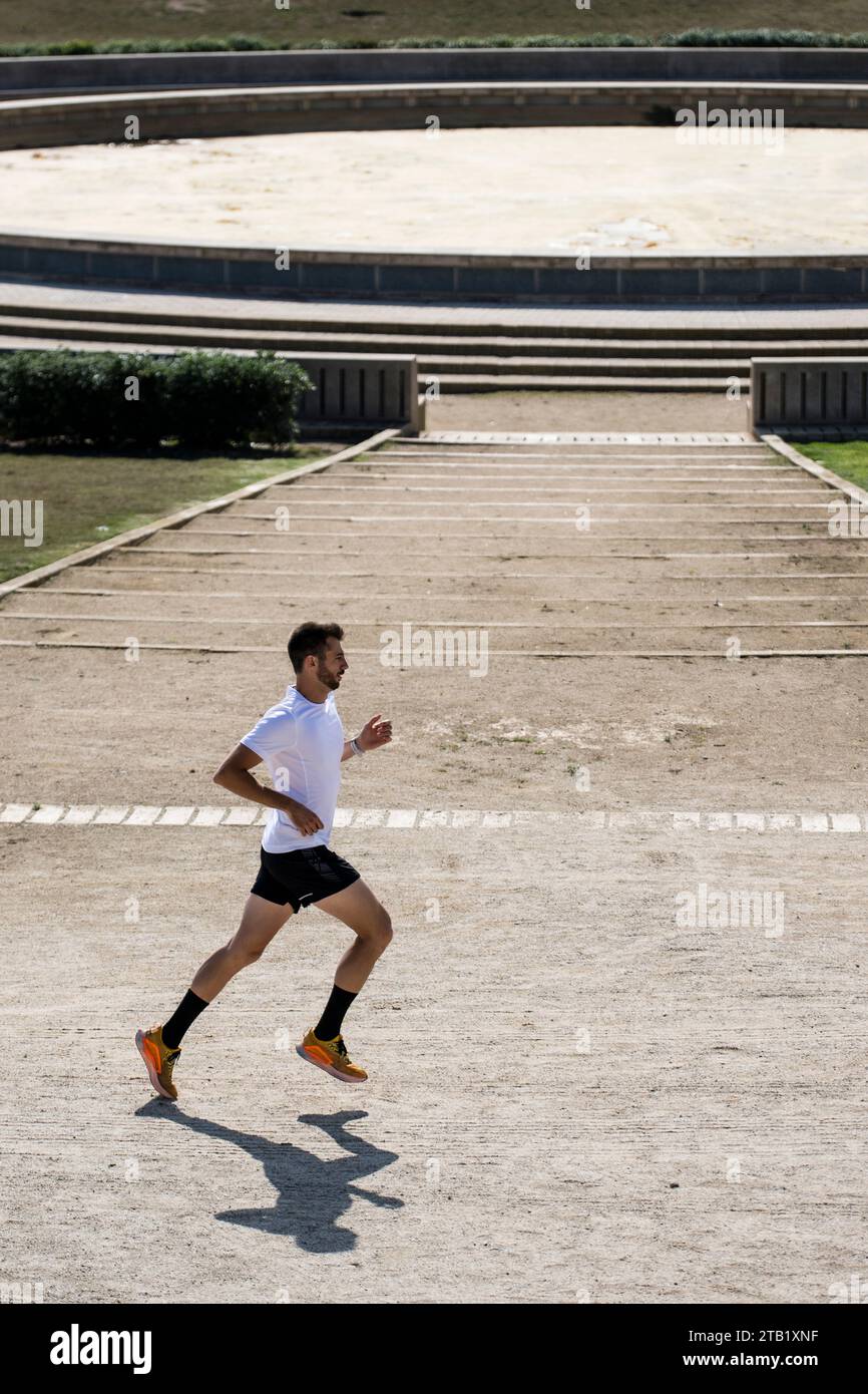 Side view of fit man running next to a athletic ancient stadium Stock ...