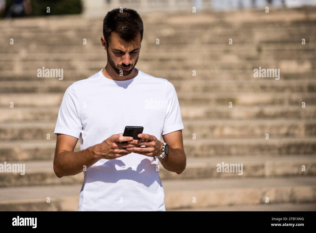 Fit male athlete checking smartphone for a running training outside ...
