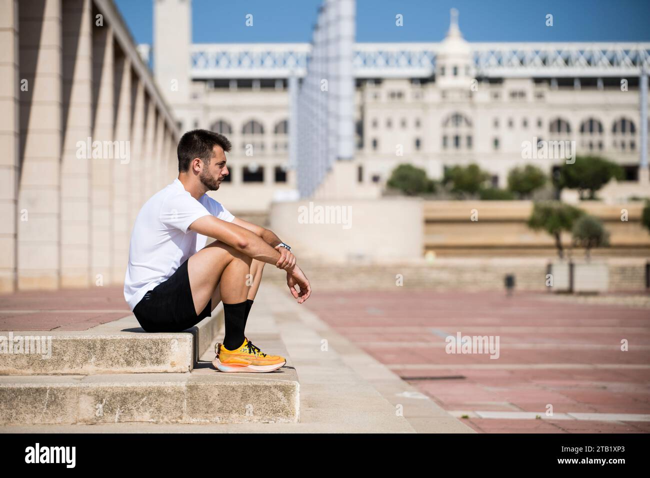 Runner man resting sitting in stairs with a stadium in background Stock ...