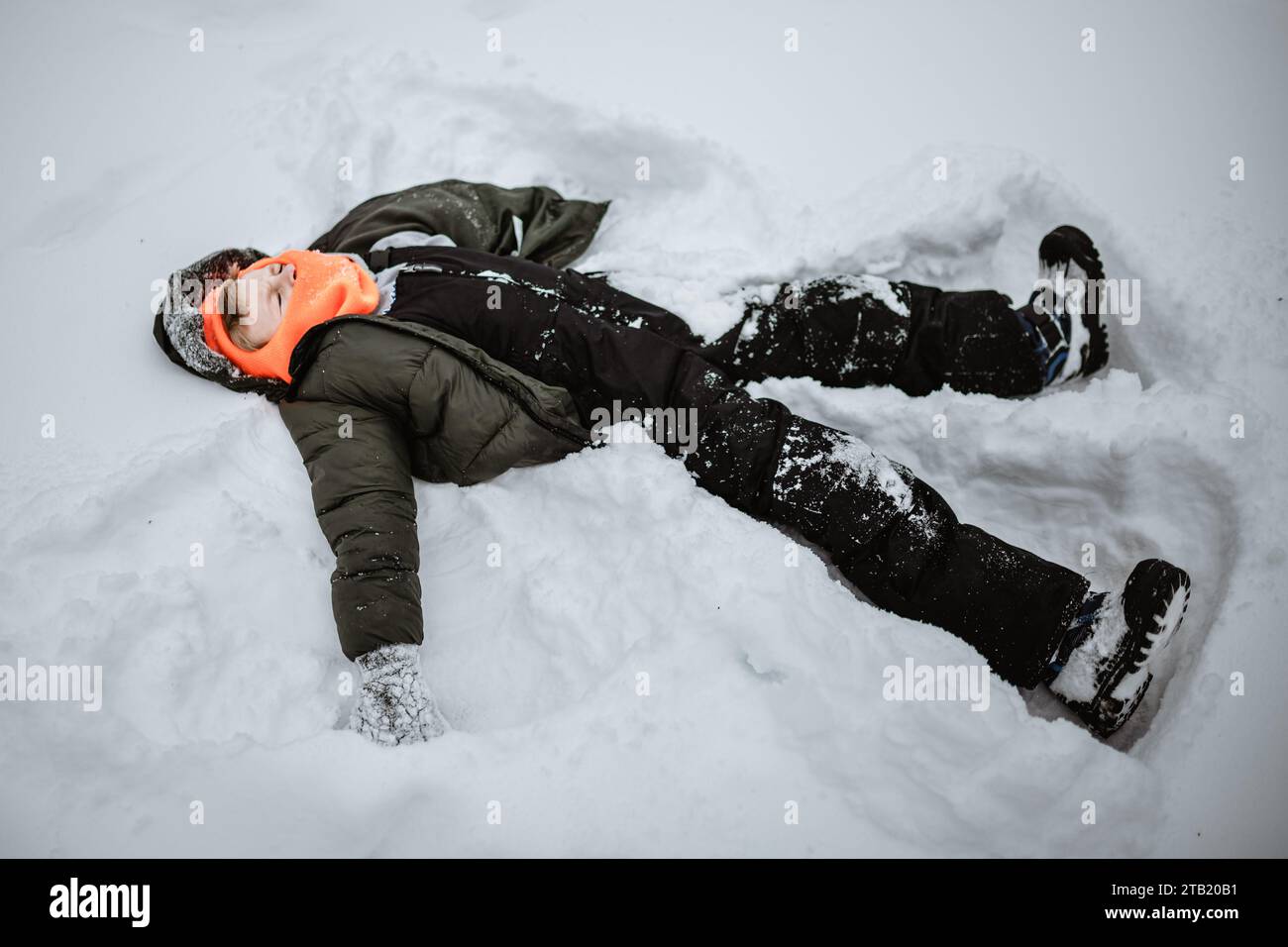 Boy laying in deep snow making snow angel Stock Photo - Alamy