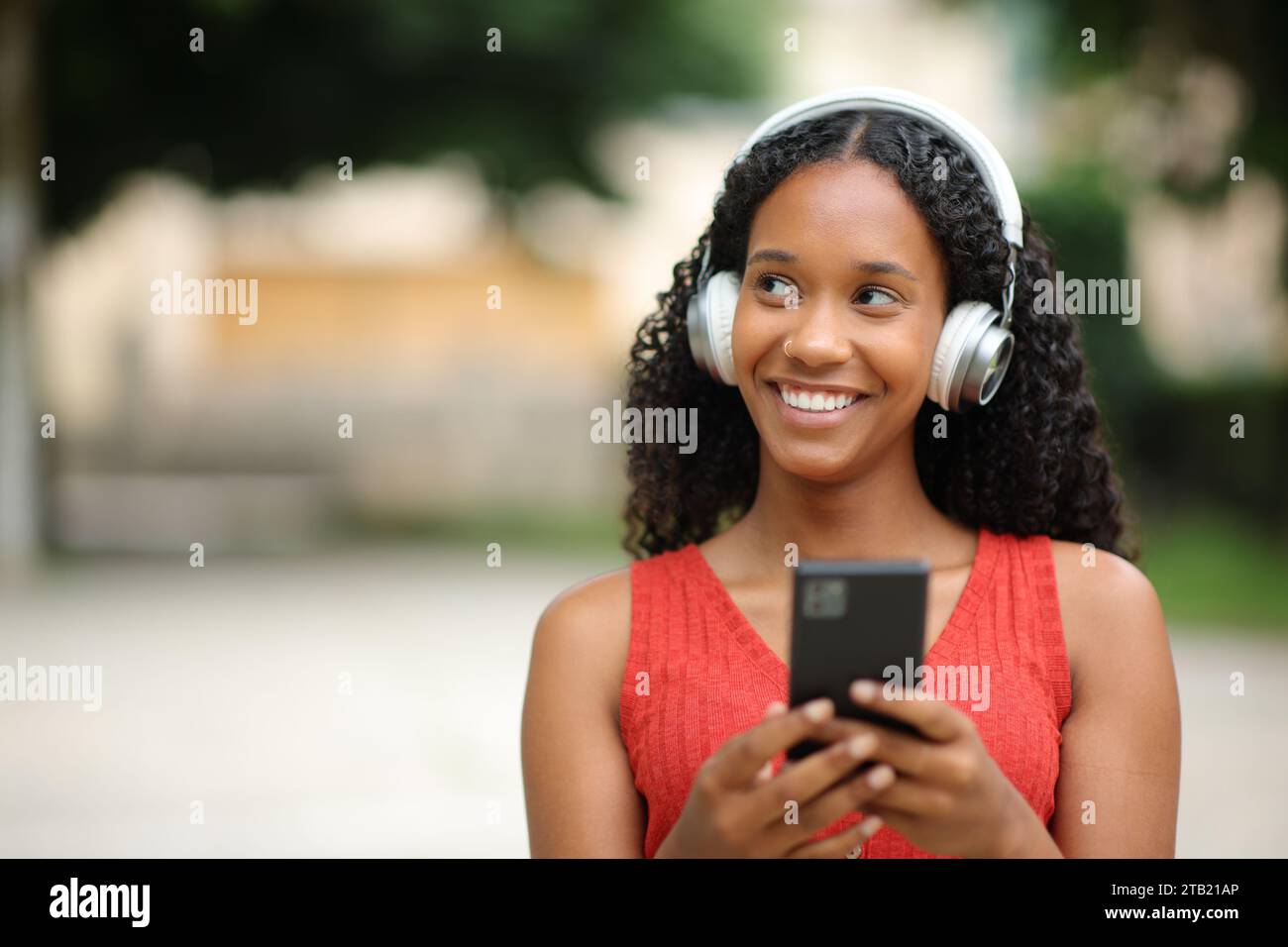 Front view portrait of a happy black woman looks at side listening to ...