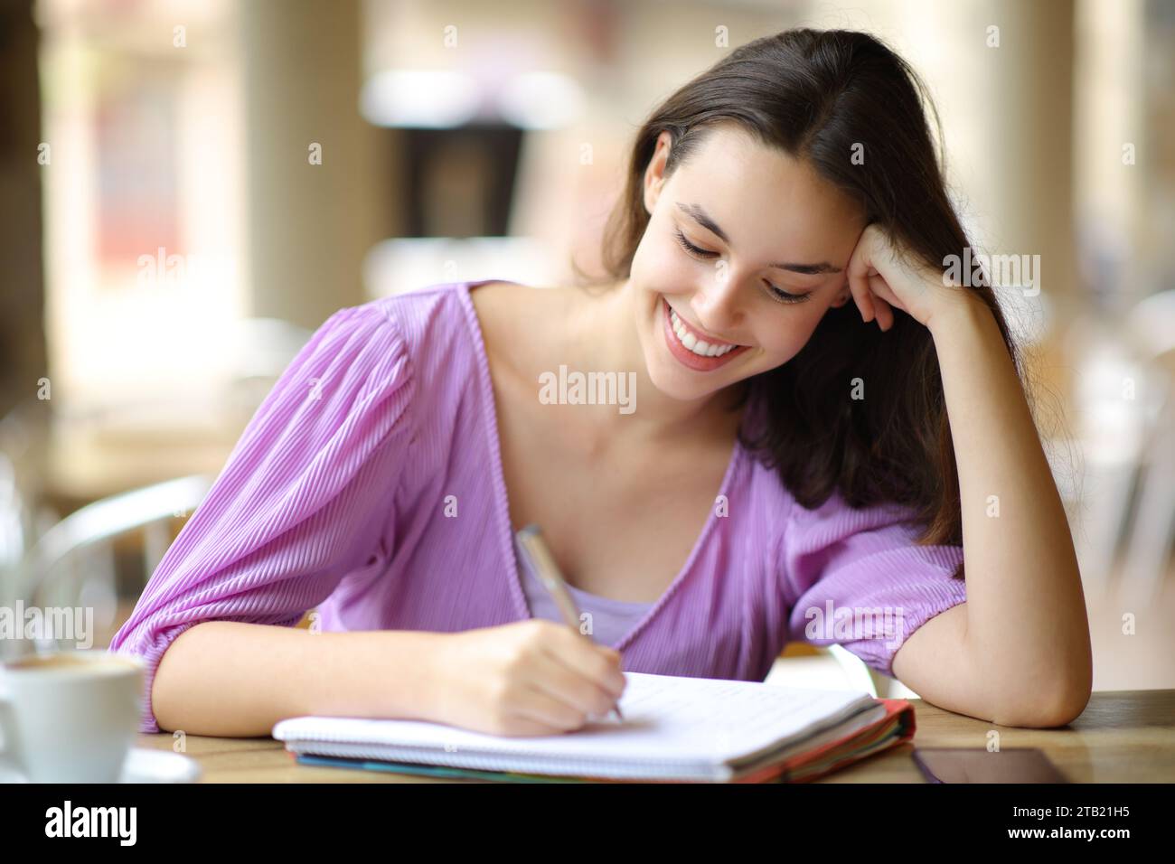 Happy student taking notes in a coffee shop terrace Stock Photo - Alamy