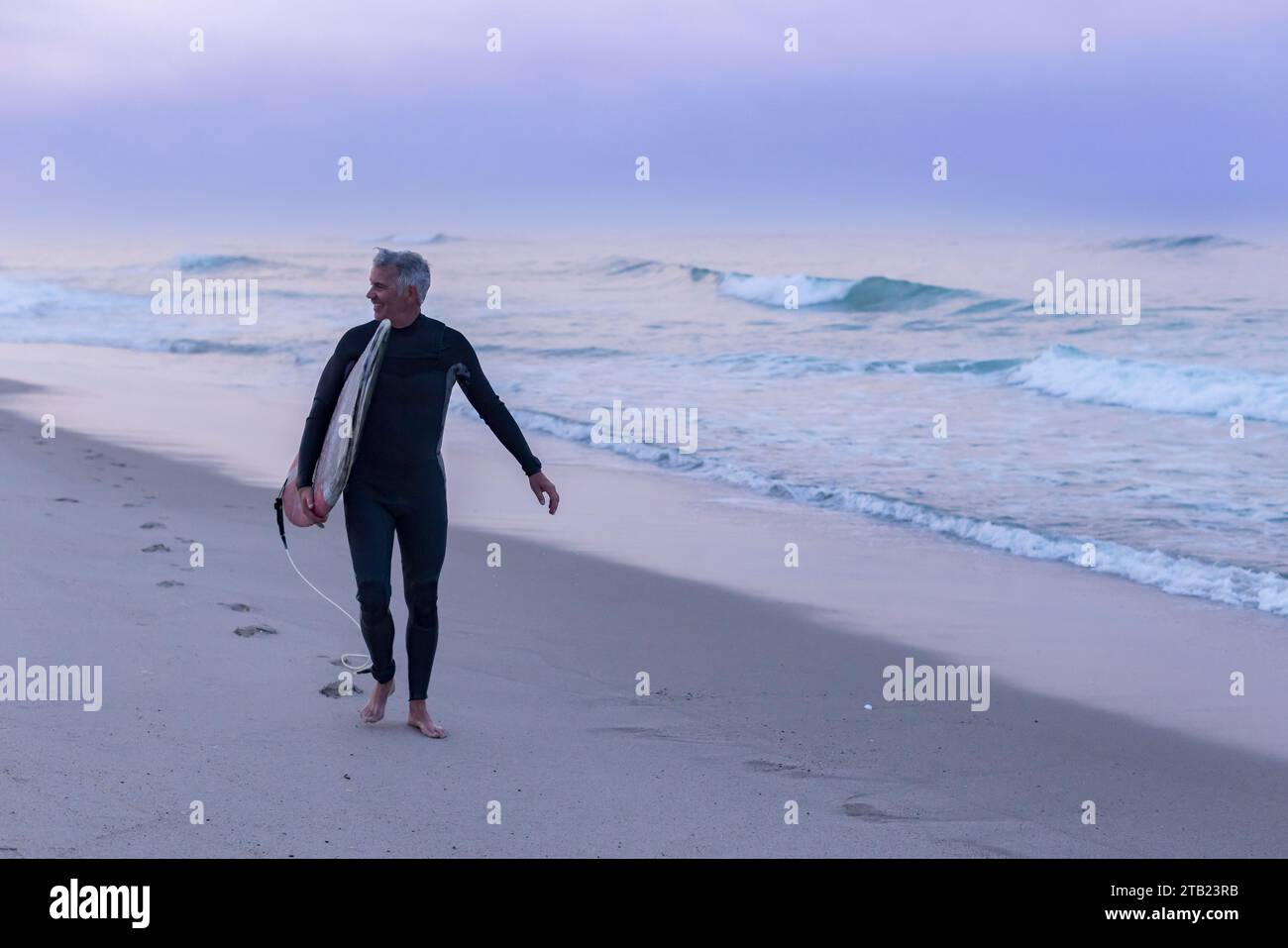 An older surfer walks on the beach with his surfboard on Cape Cod Stock ...