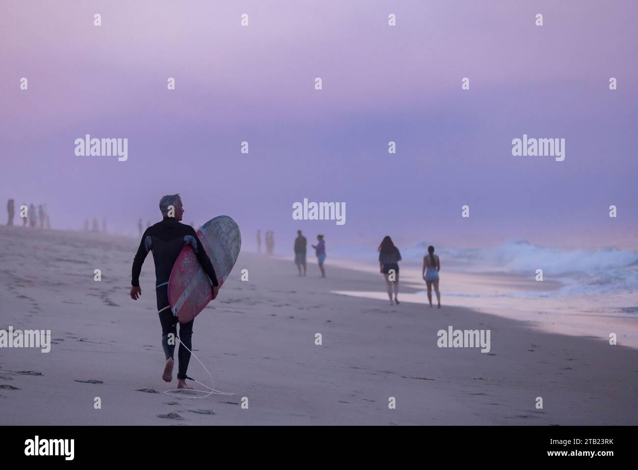 An older surfer walks on the beach with his surfboard on Cape Cod Stock ...