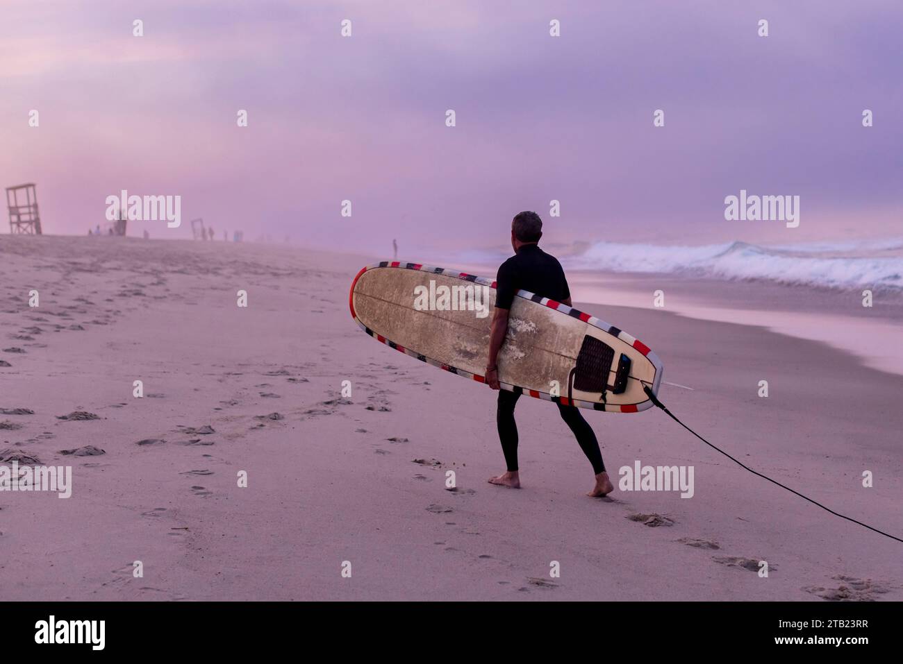 An older surfer walks on the beach with his surfboard on Cape Cod Stock ...