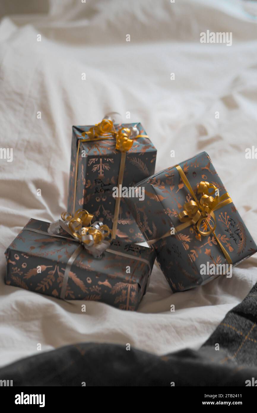 Three gift boxes wrapped in festive wrapping paper and adorned with ...