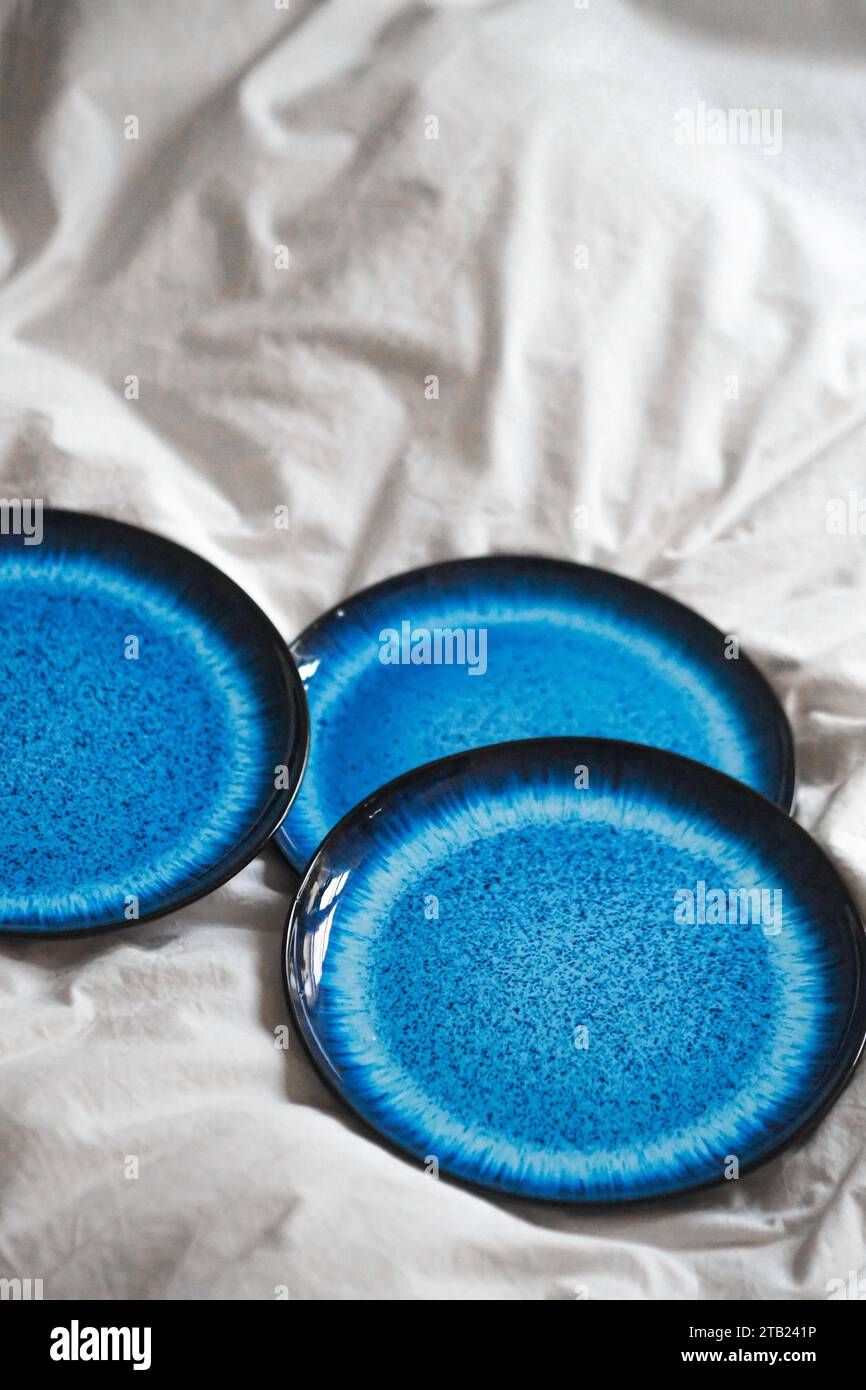 A close-up view of three blue ceramic plates stacked on top of a white ...