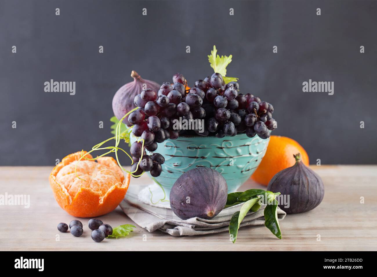 Grape, tangerine and figs fruit in blue bowl on wooden table, healthy ...
