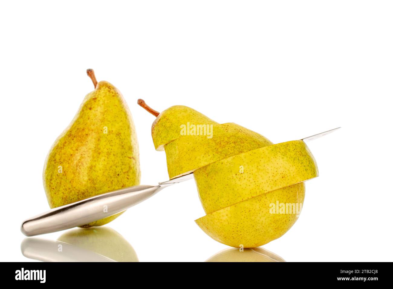 One bright yellow pear cut into pieces with a metal knife and one whole ...